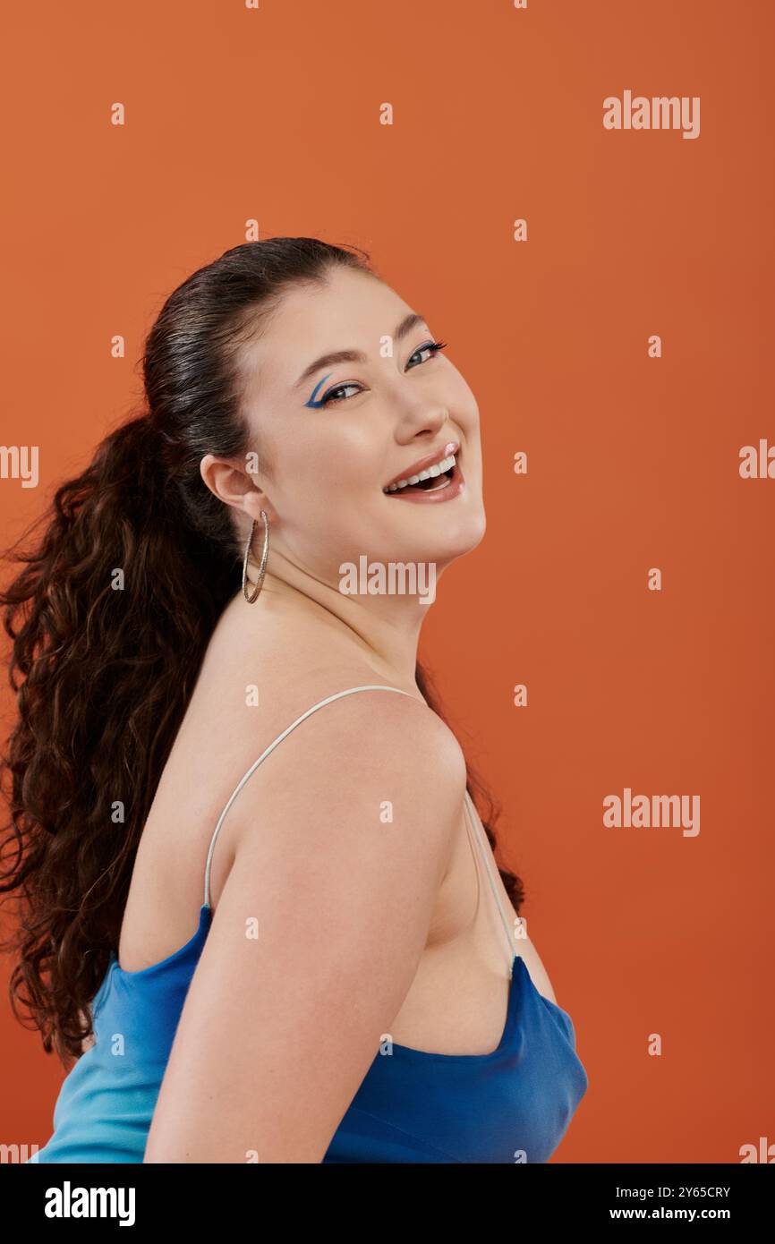 A young, beautiful plus size woman poses gracefully in a blue dress ...