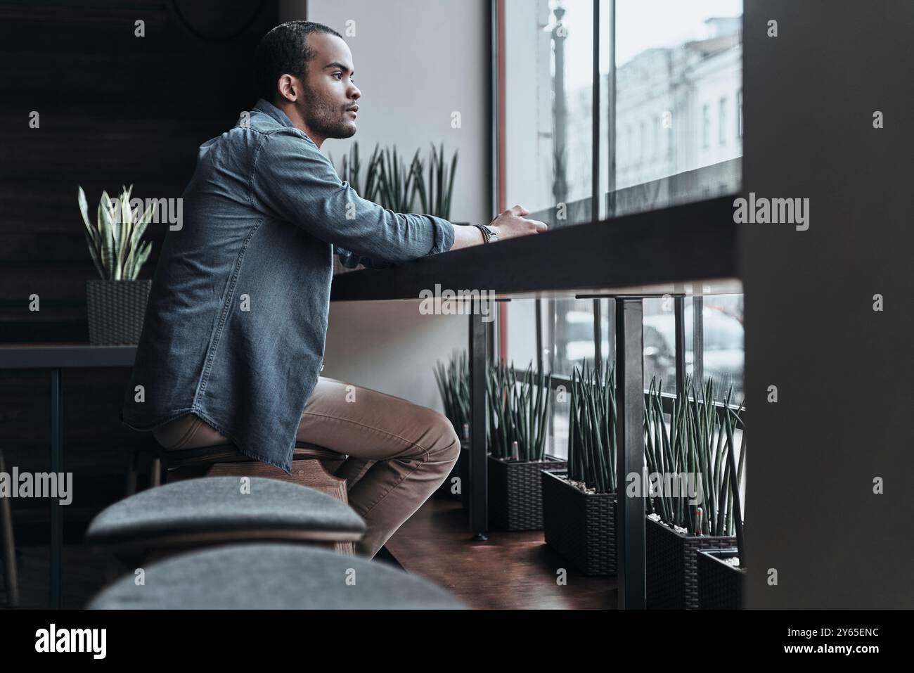 Taking some time to think. Thoughtful young man looking outside while ...