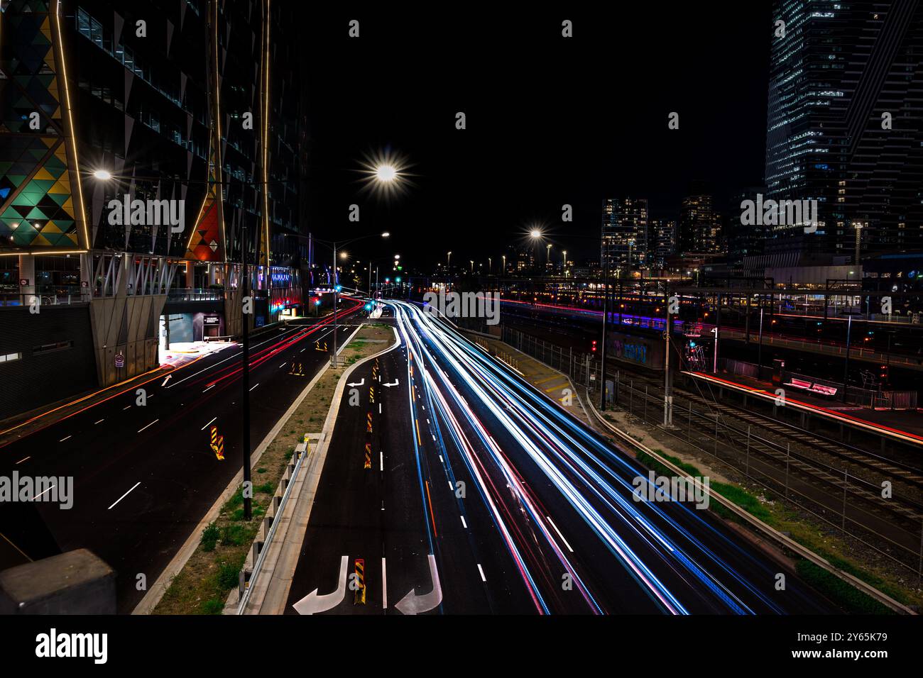 Traffic light trails on Wurundjeri Way and train track outside the ...
