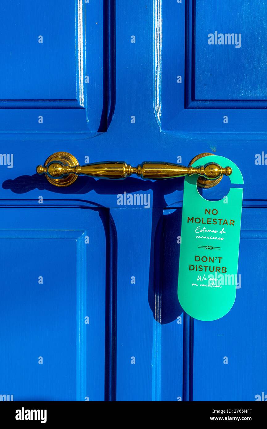 Vibrant blue door detailed with a gold handle showing a No Molestar, Do ...
