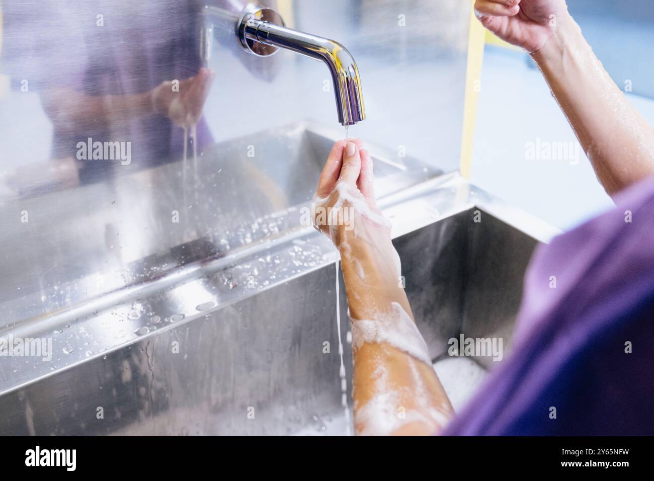 A healthcare worker is captured meticulously cleaning their arms and ...