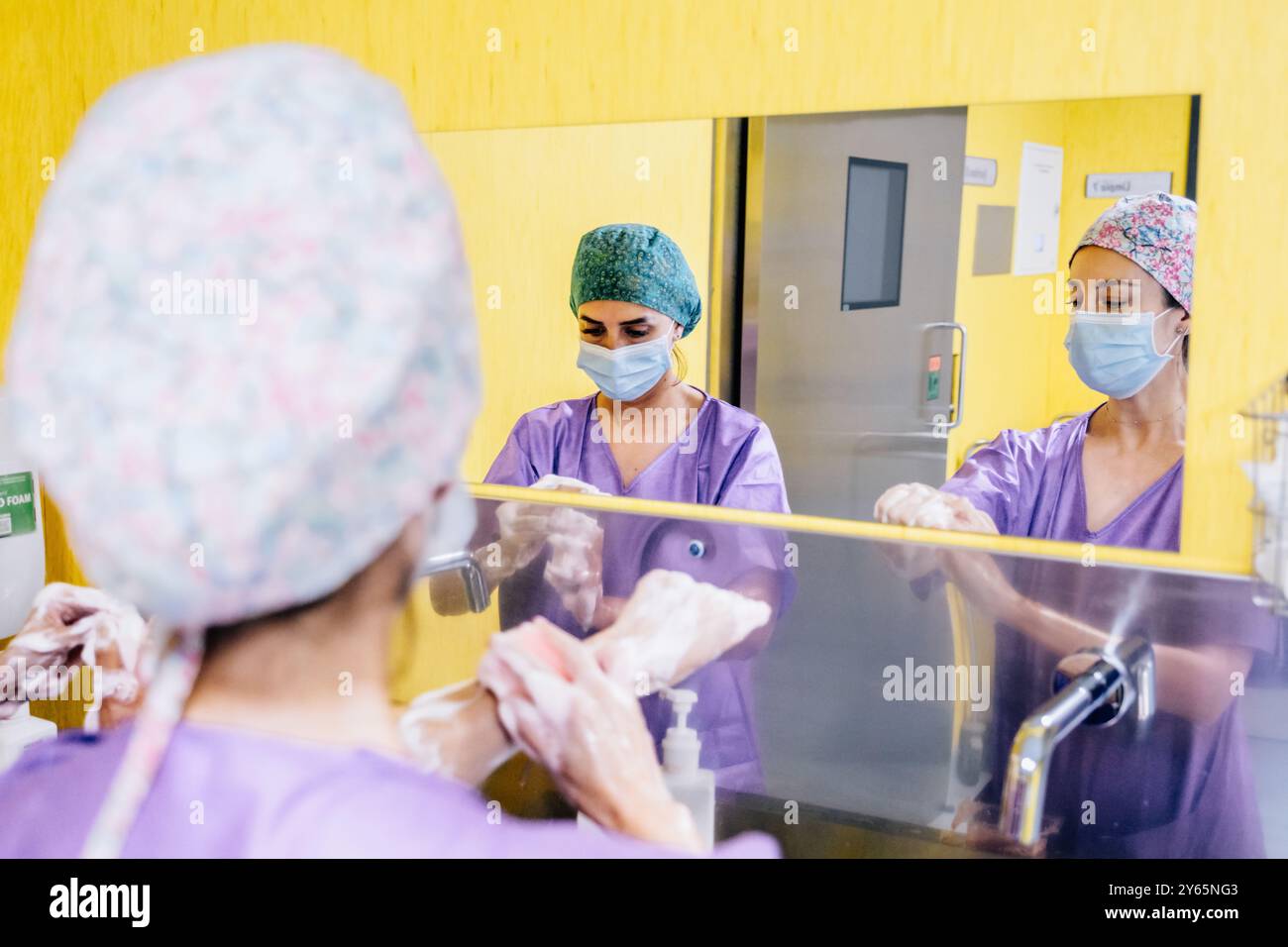 Two female surgeons diligently wash their hands in a hospital setting, maintaining high hygiene ...