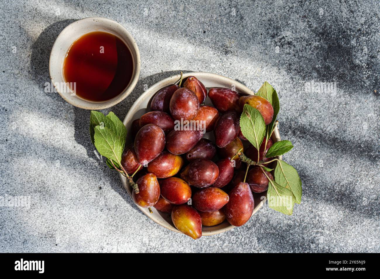 Top view of a bowl filled with organic ripe plums surrounded by fresh ...