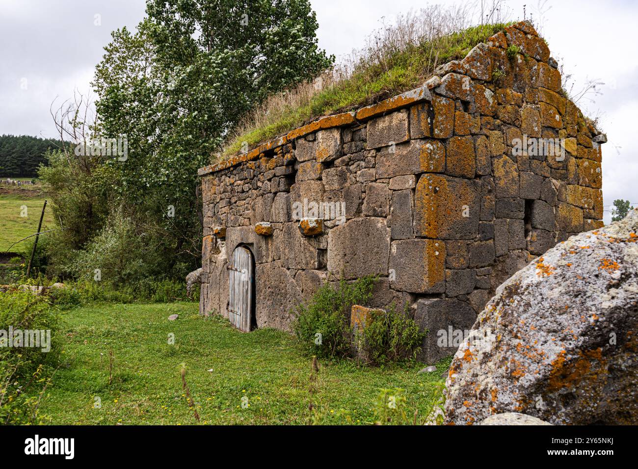 A historic stone building, overgrown with vegetation, stands in the ...