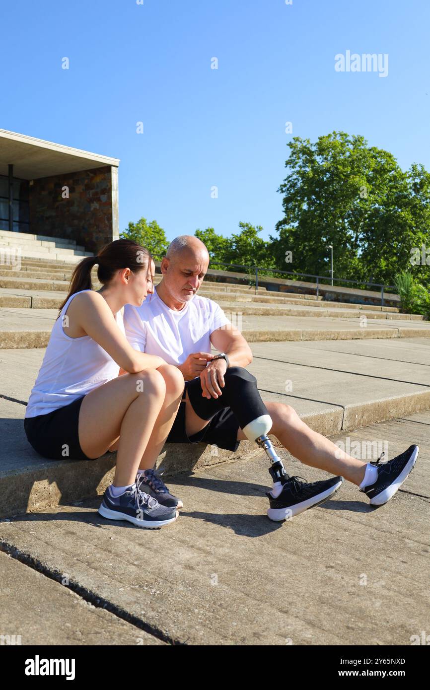 A man with an amputated leg and a prosthetic sitting on steps outdoors ...