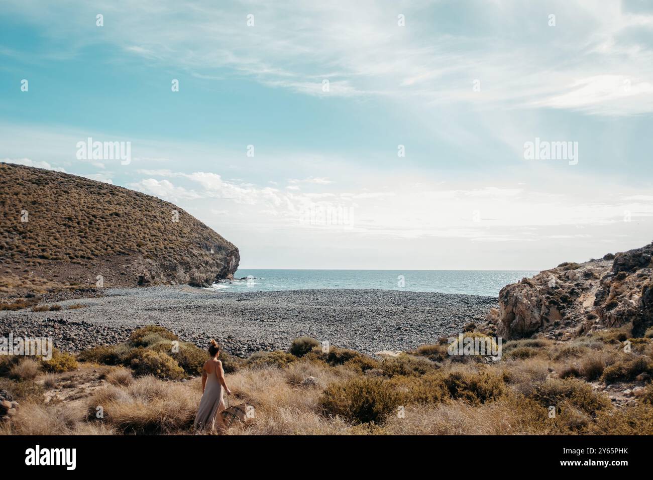 Back view of unrecognizable female walking towards the rugged coastline ...