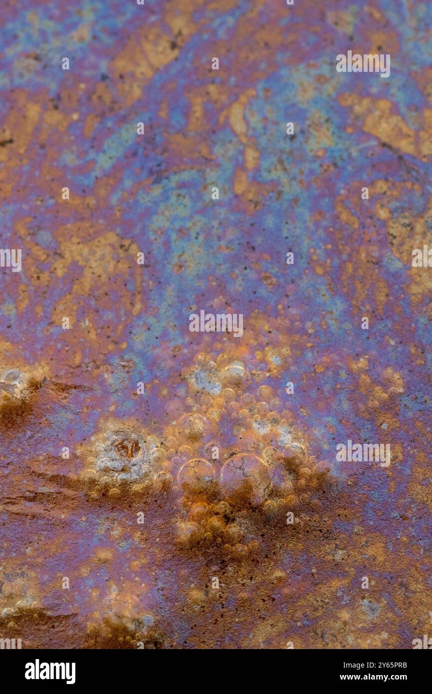 This image captures a small puddle exhibiting a mesmerizing spectrum of ...