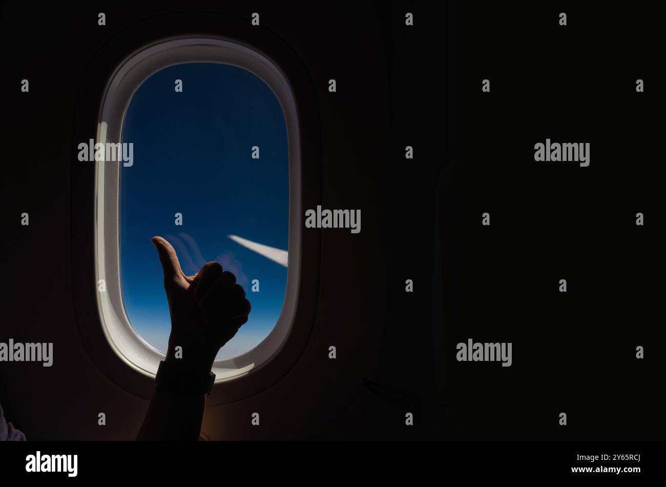 Cropped unrecognizable passenger's hand framing the view of the sky and ...