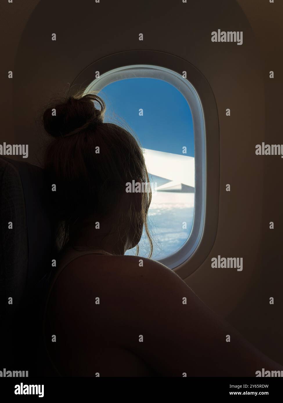 Side view of unrecognizable person looking out airplane window, holding ...