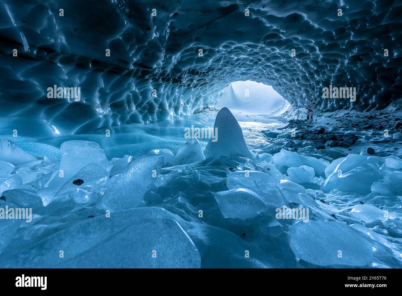 Captivating view inside an ice cave with a tunnel of rugged, textured icy walls and natural ...