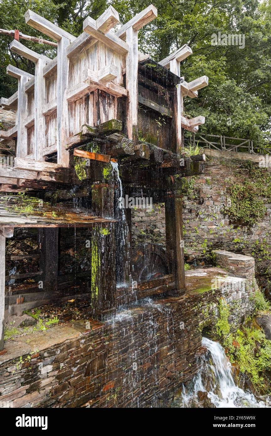 A close-up view of a traditional wooden water mill, actively spinning ...