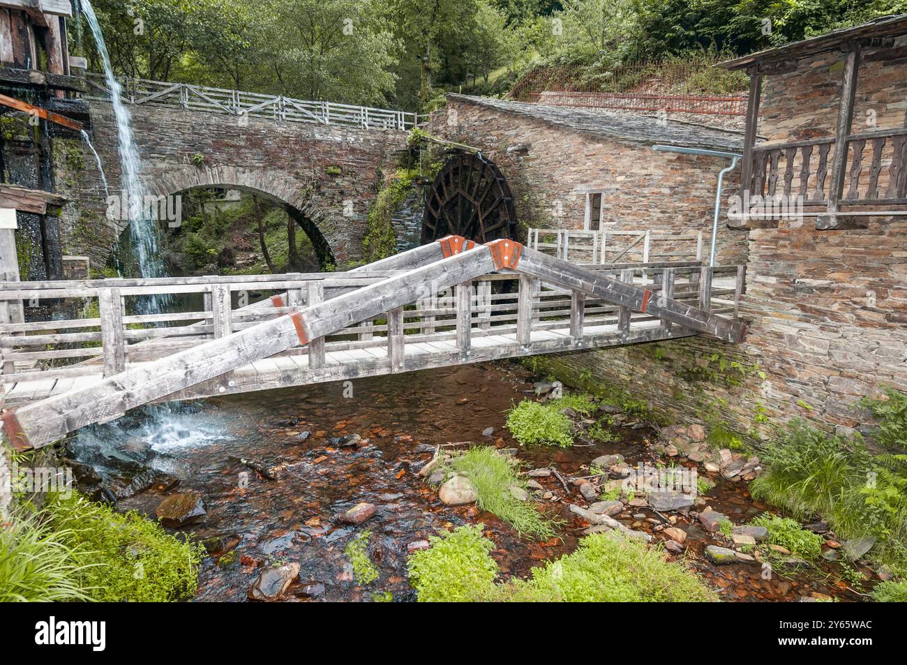 A scenic view of an old water mill with a large waterwheel, adjacent ...