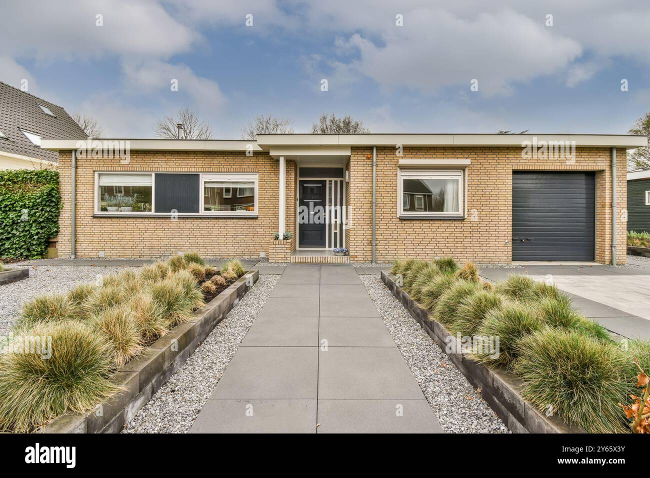A contemporary single-story house featuring a neatly arranged garden ...