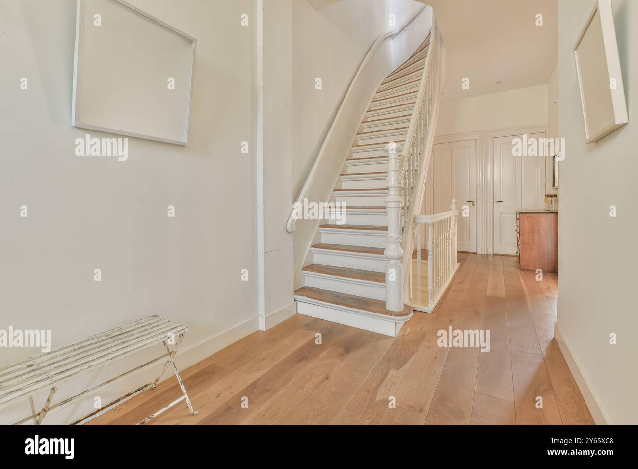 A well-lit hallway featuring a white elegantly curved staircase ...