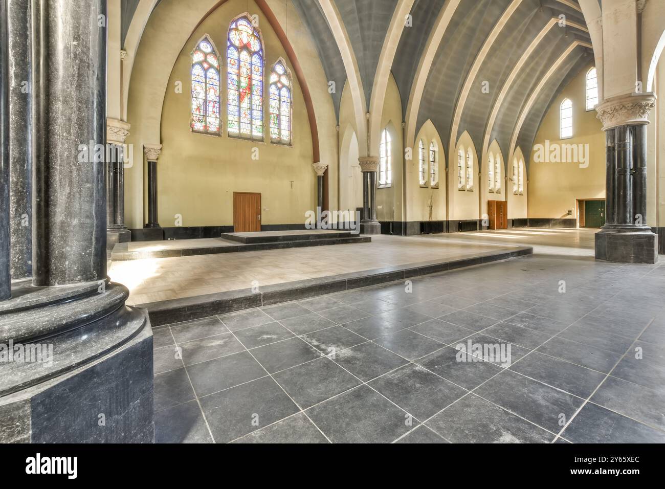 "An empty church interior with high ceilings, stained-glass windows ...