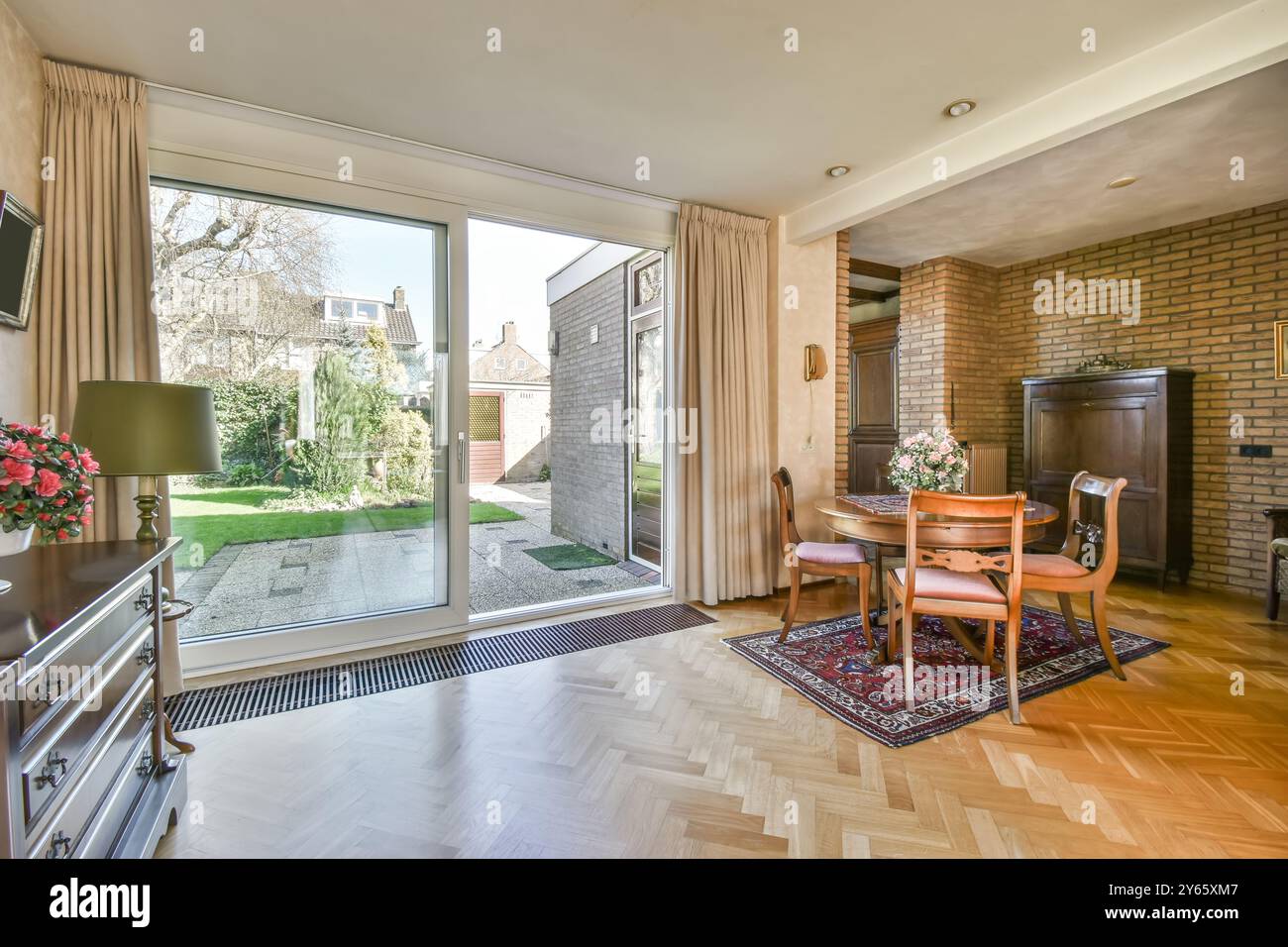A well-lit living room features parquet floors, a dining area, and ...