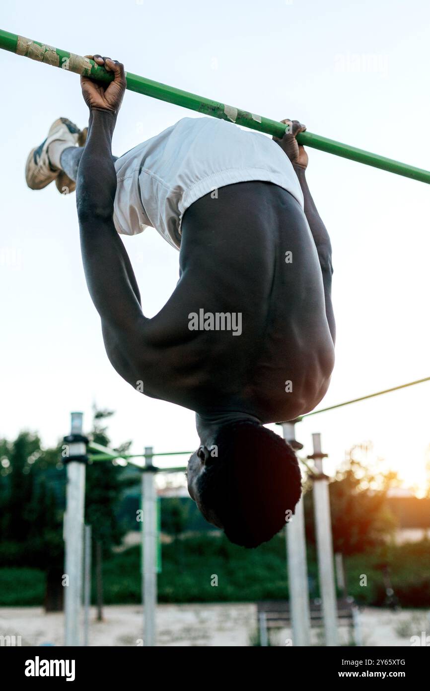 A concentrated athlete performs an exercise on an outdoor bar ...