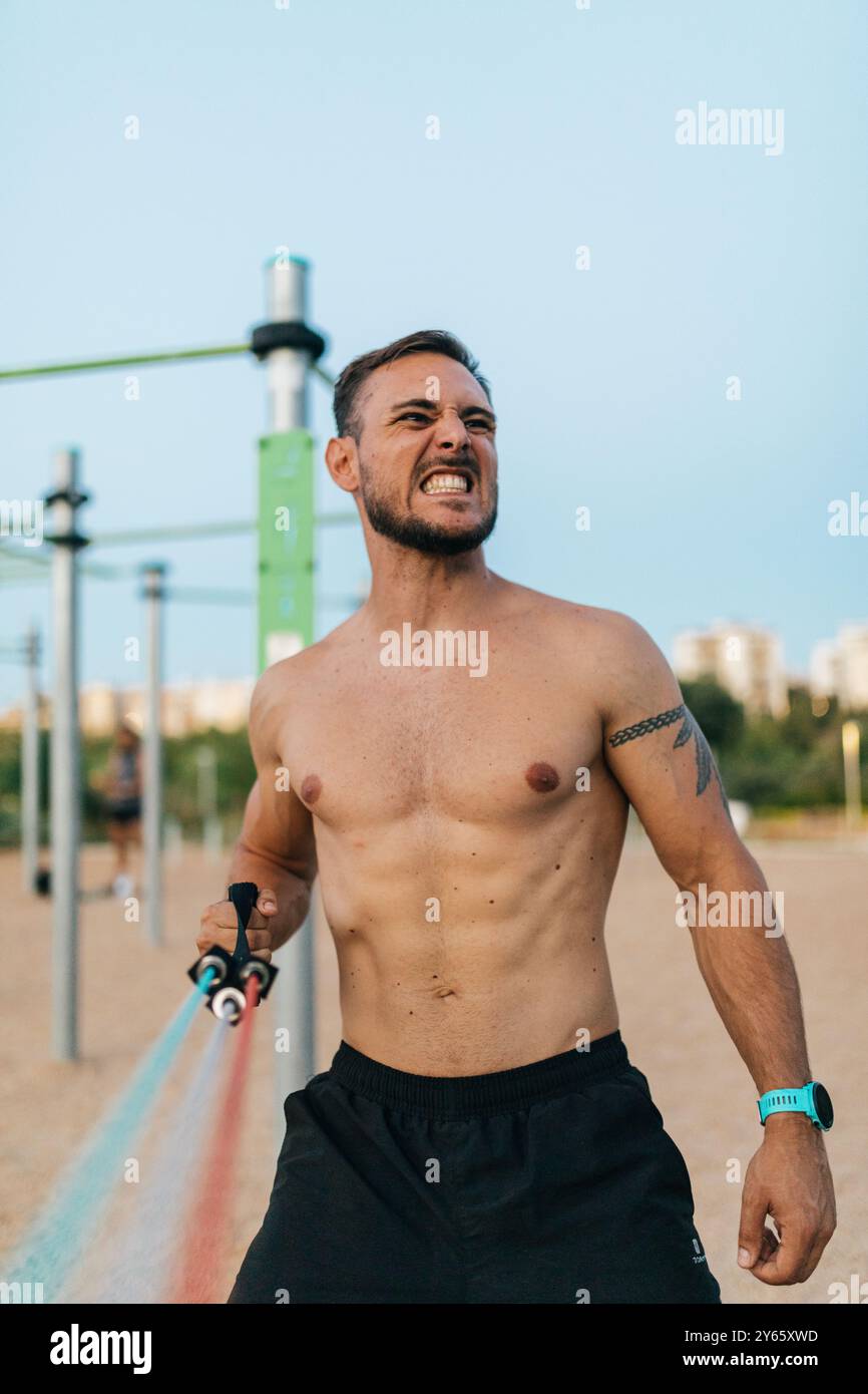 A focused man engages in intensive calisthenics workout at an outdoor ...