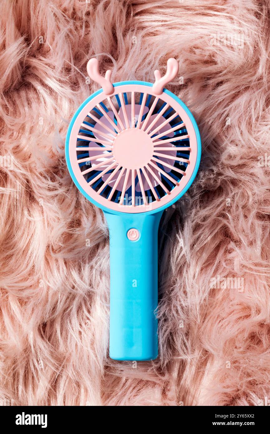 A blue handheld fan with whimsical reindeer antlers, on a soft pink ...