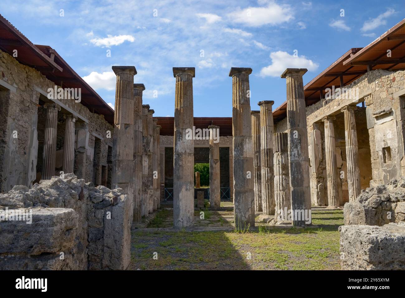 The historic ruins of Pompeii, featuring tall, weathered columns and remnants of stone ...