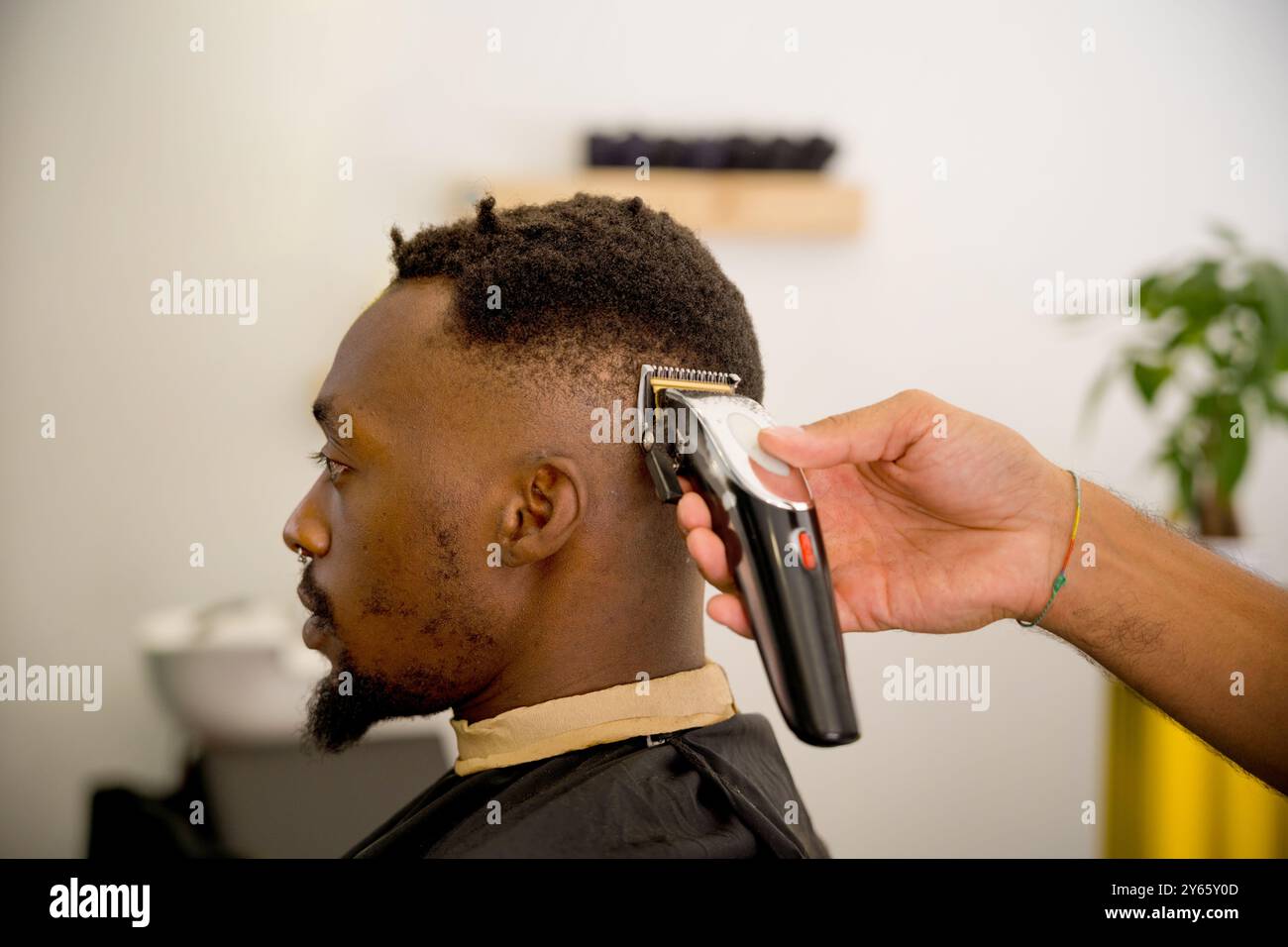 A professional barber trims and styles the hair of a black man using ...