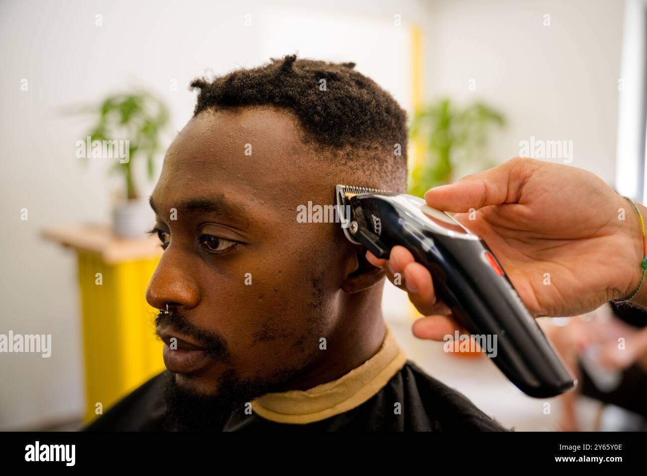 A close-up view of a skilled barber giving a precise haircut to a black ...