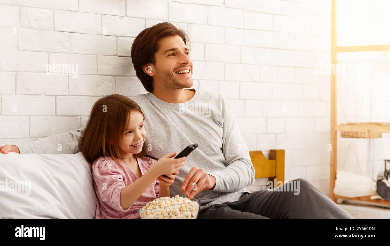 Girl watching TV with her young dad, eating popcorn Stock Photo - Alamy