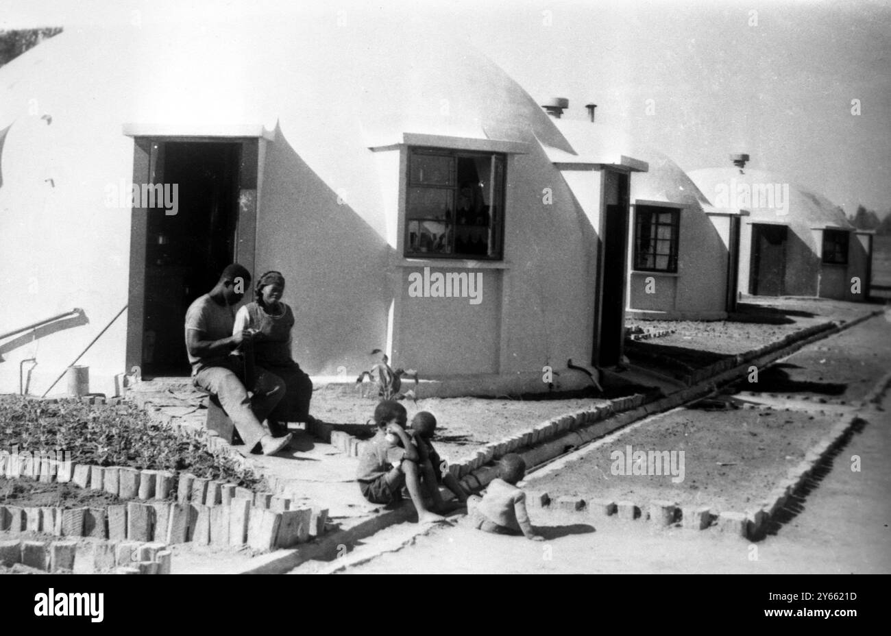 An African gold mine worker , with his wife and children , seated in ...