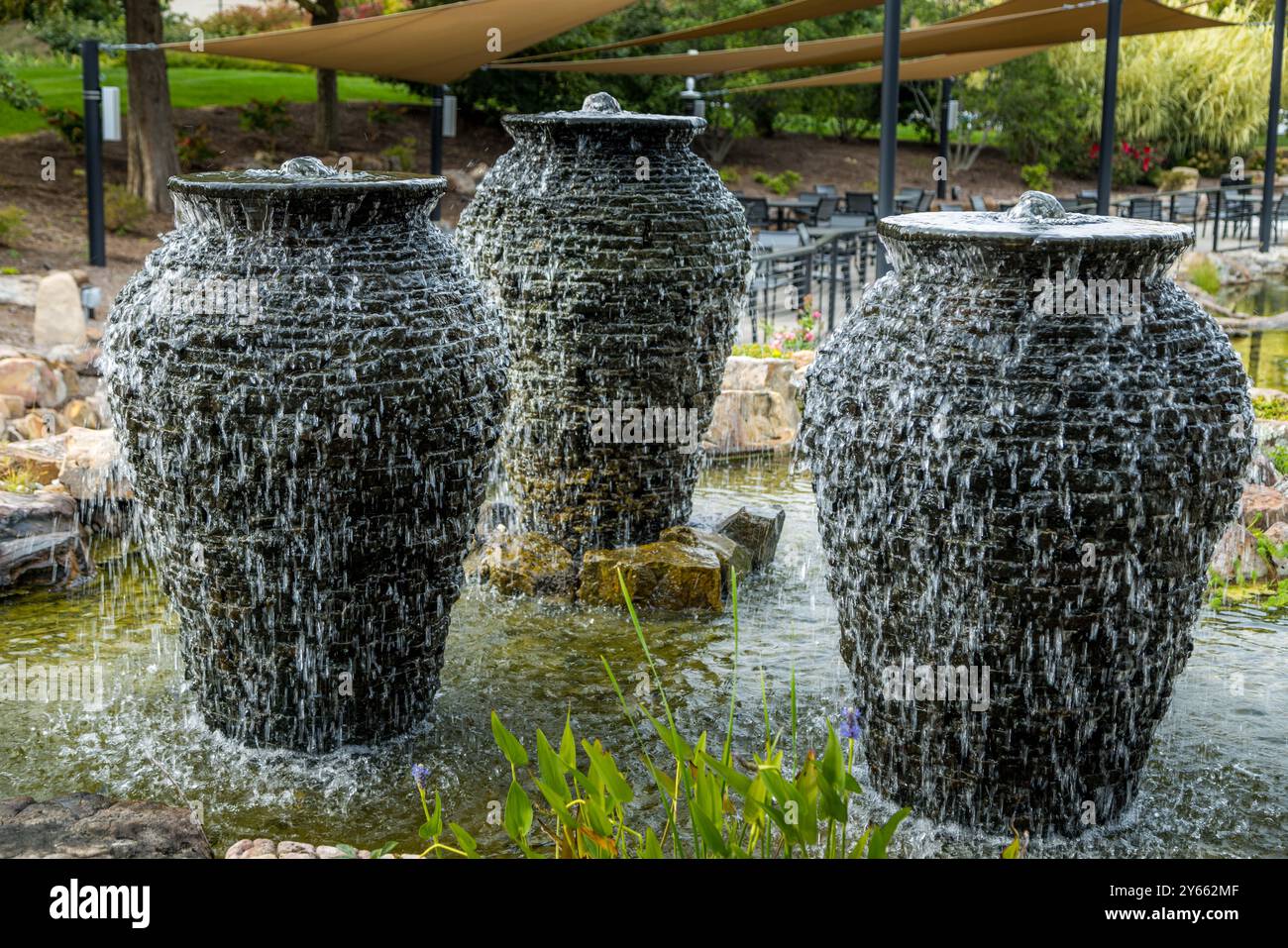 Three large stone water fountains in a beautifully landscaped garden ...