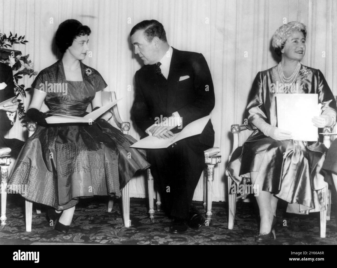 Norman Hartnell, the Royal fashion designer, explains a point to ...