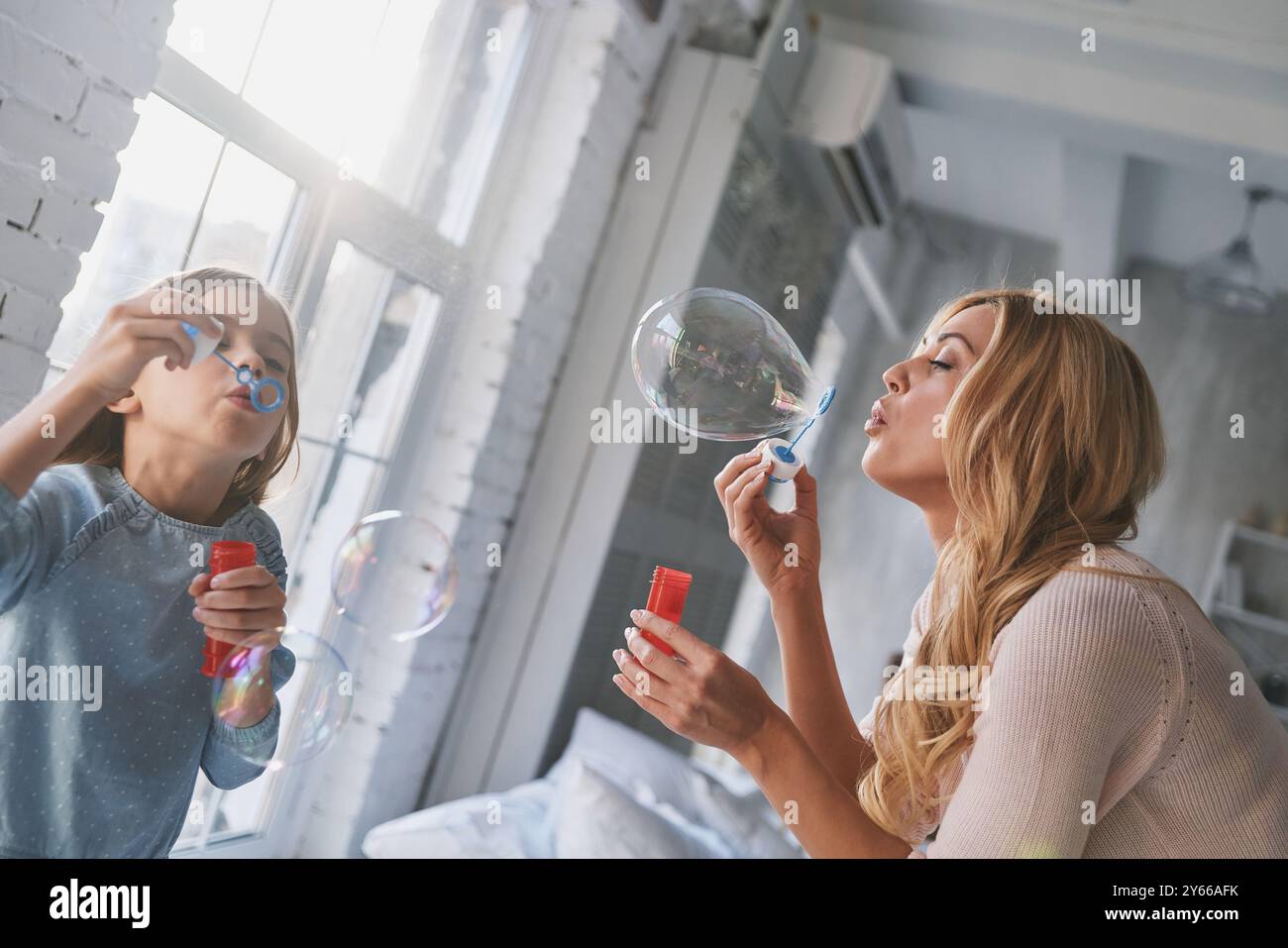 Family bonding. Mother and daughter blowing soap bubbles while spending ...