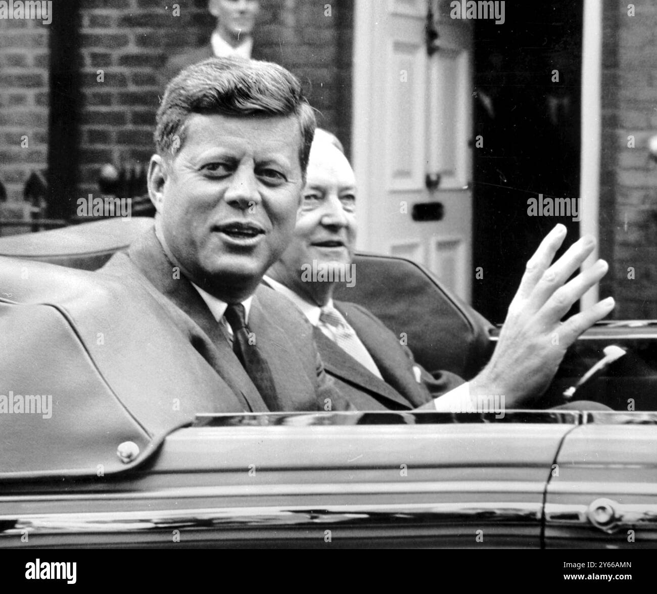 President John F Kennedy waves in an open car leaving Buckingham Palace ...