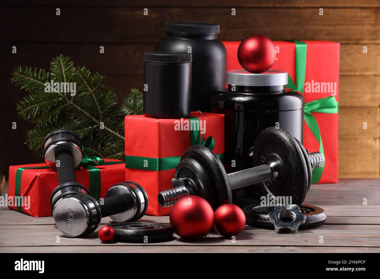 Dumbbells, containers with supplement and Christmas decor on wooden ...