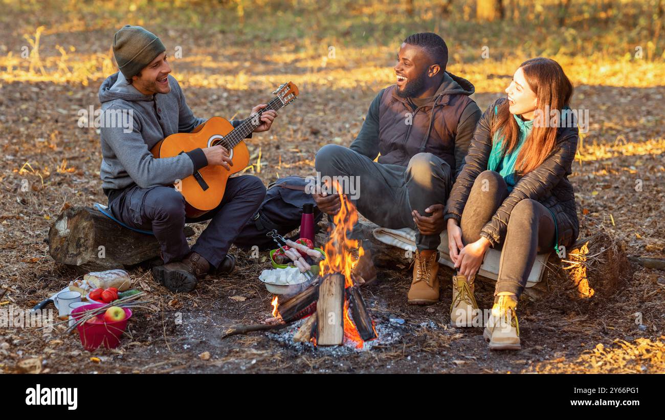 Group of people camping and singing in autumn woods Stock Photo - Alamy