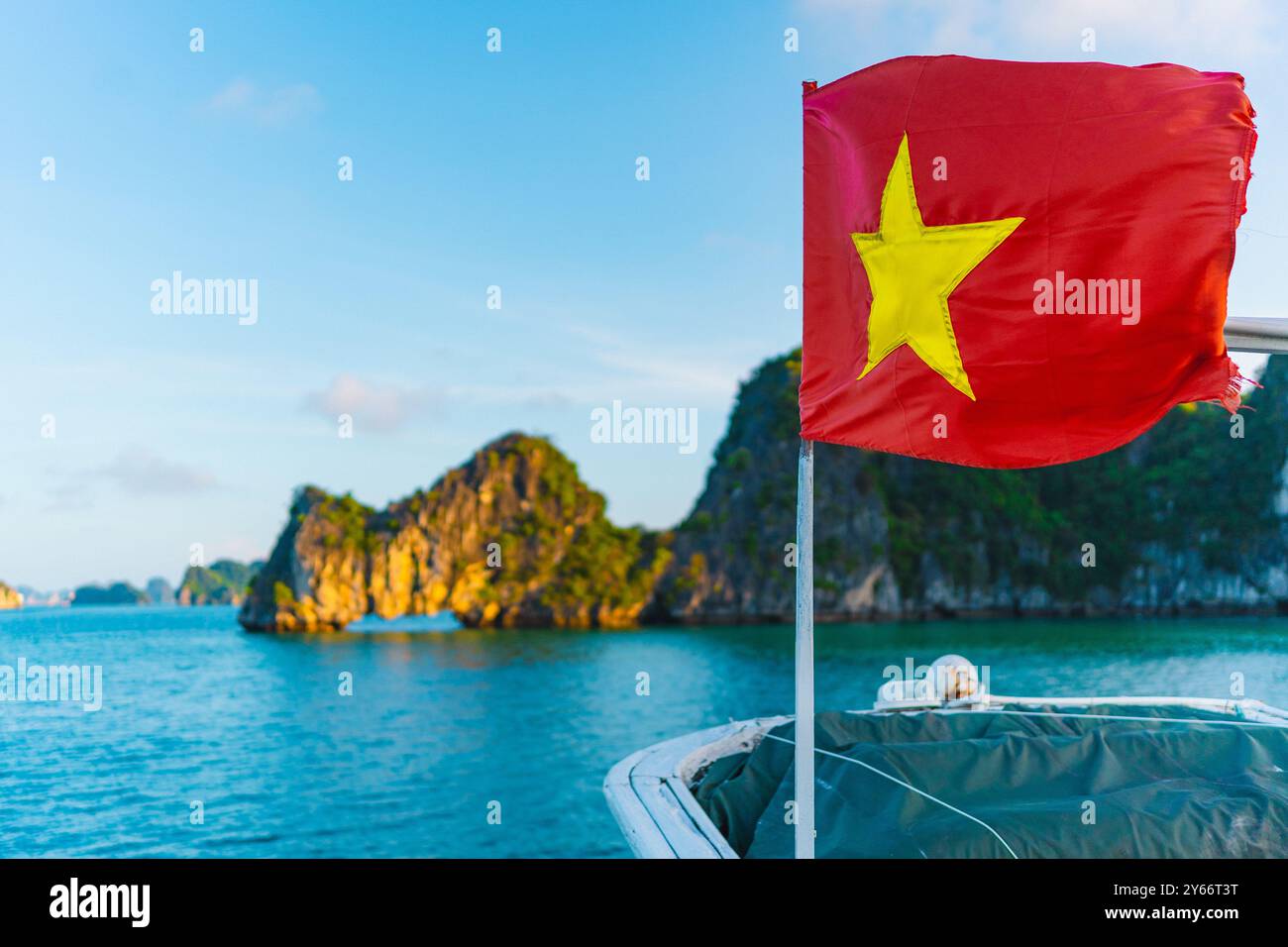 The red flag of Vietnam waves on a boat sailing through the landmark Ha ...