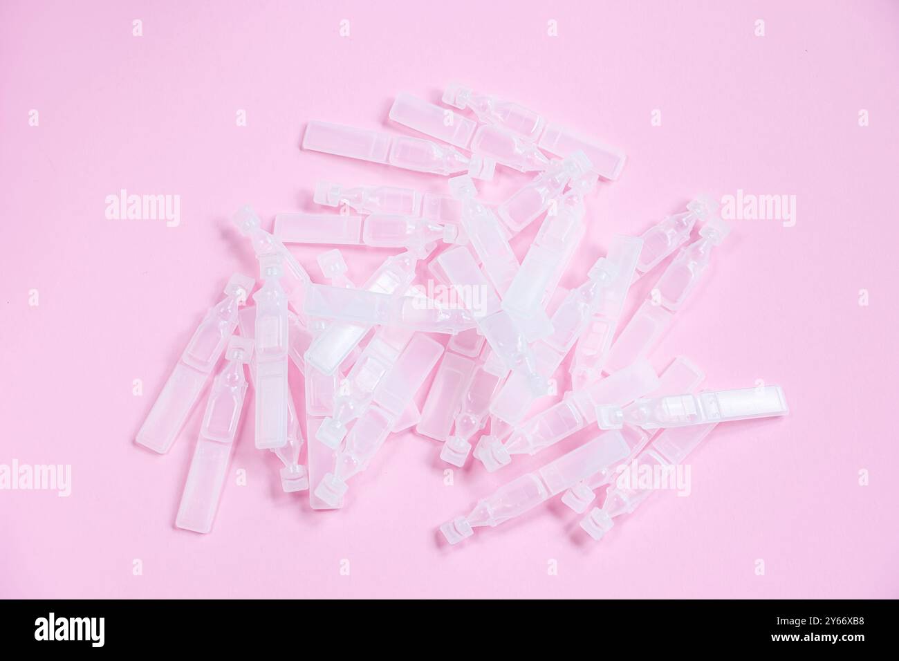 Medical eye drops in plastic pipettes on pink background. Pile of empty ...