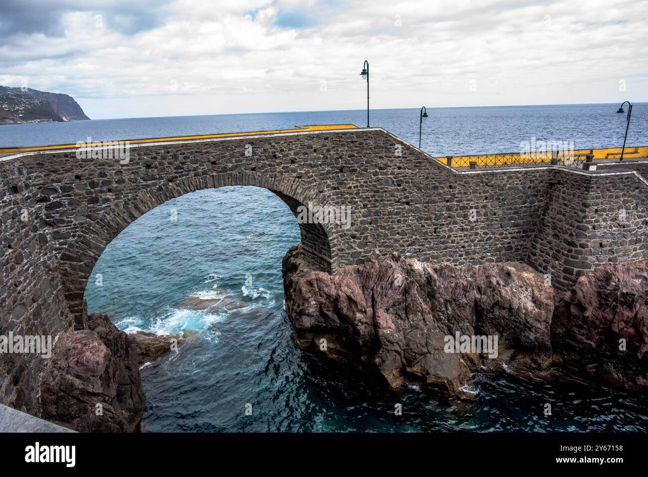 old stone bridge between lava rocks and The Atlantic Ocean at Ponta Do ...