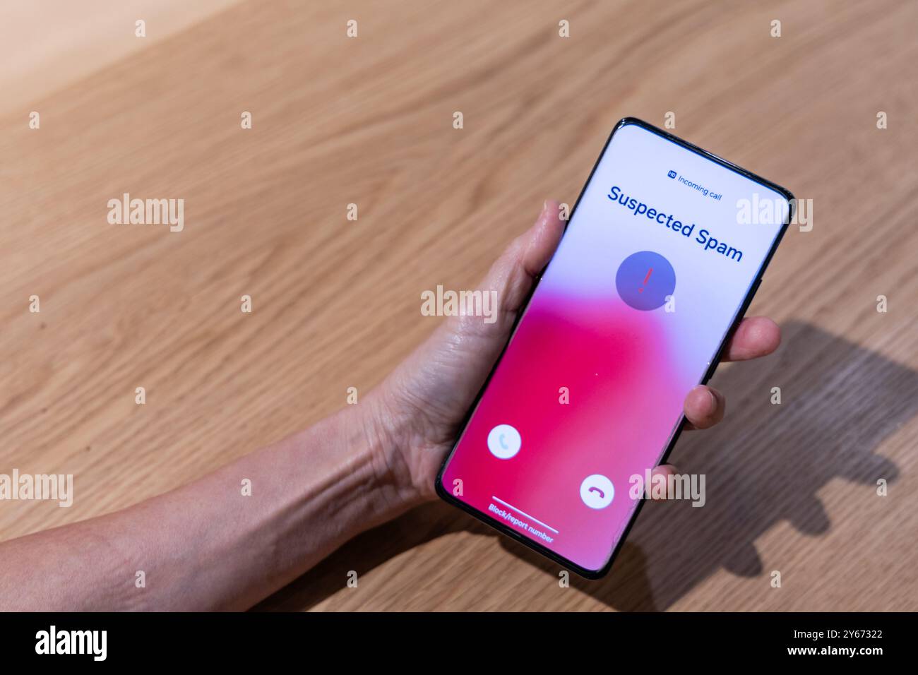 Hand holding smart phone with suspected spam incoming call warning ...