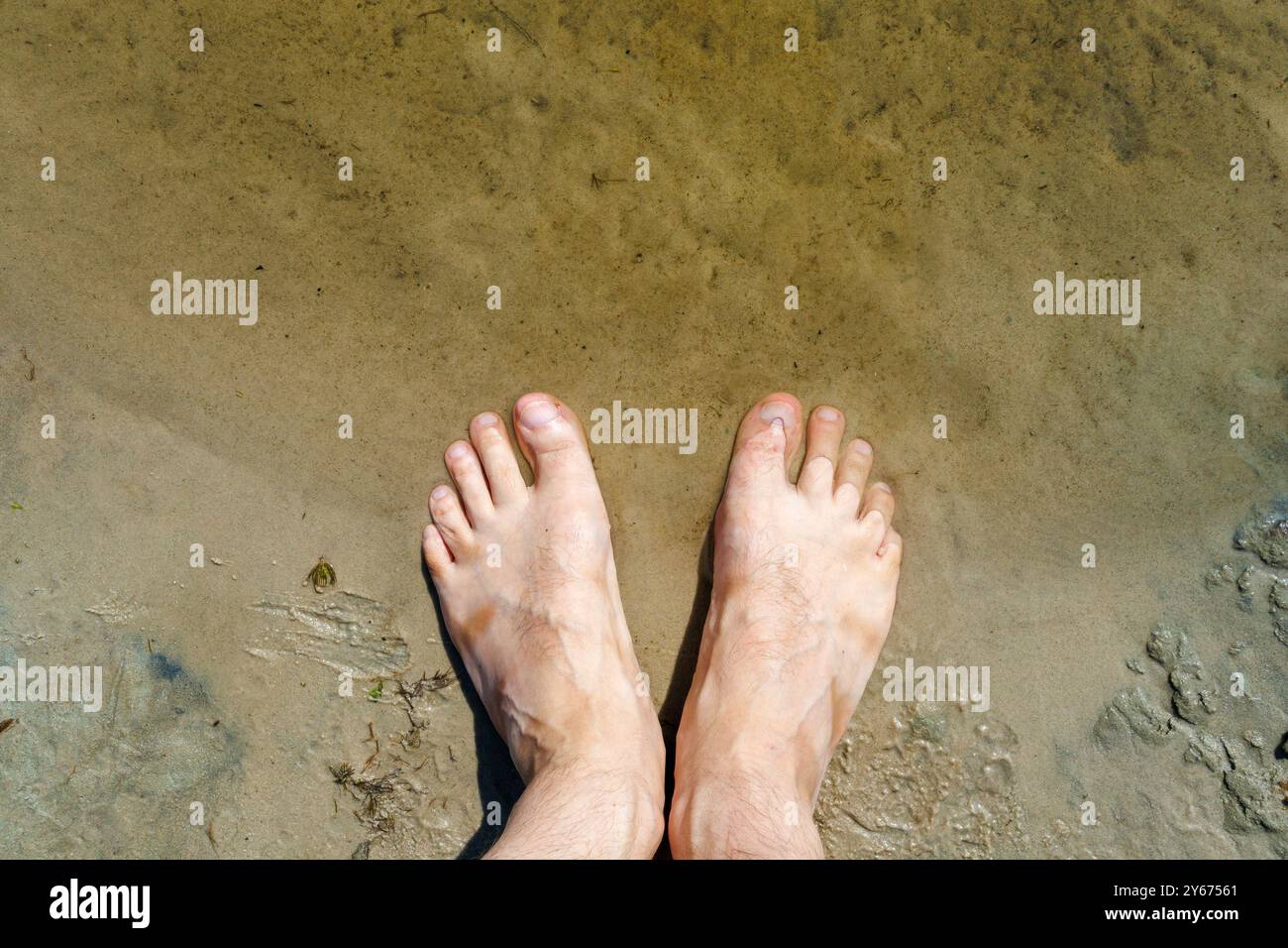 Top view of feet on the sand waiting for a wave. First person ...
