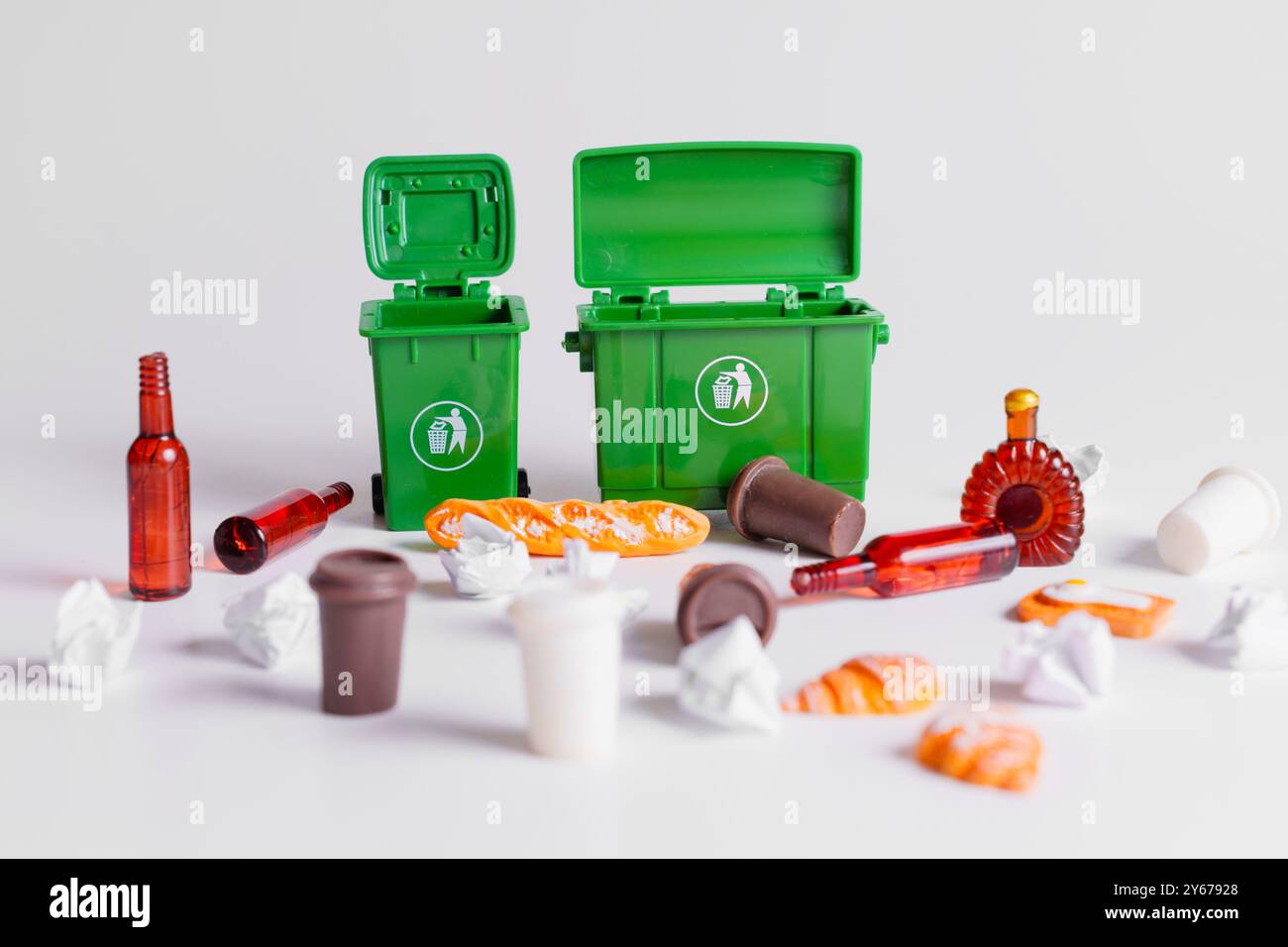 Two open miniature green trash bins and various discarded waste items ...