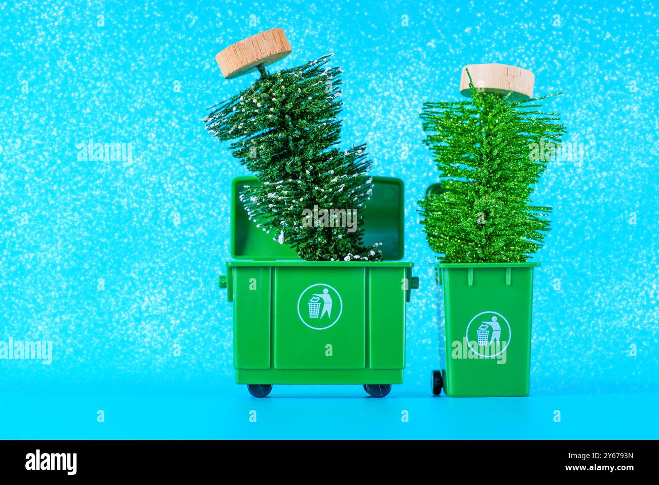 Two vibrant green Christmas trees placed in recycling bins against a ...