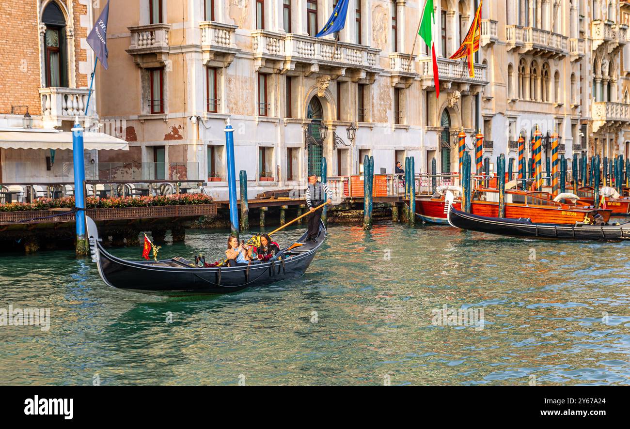 A gondolier steers his Gondola with two people enjoying a gondola ride ...
