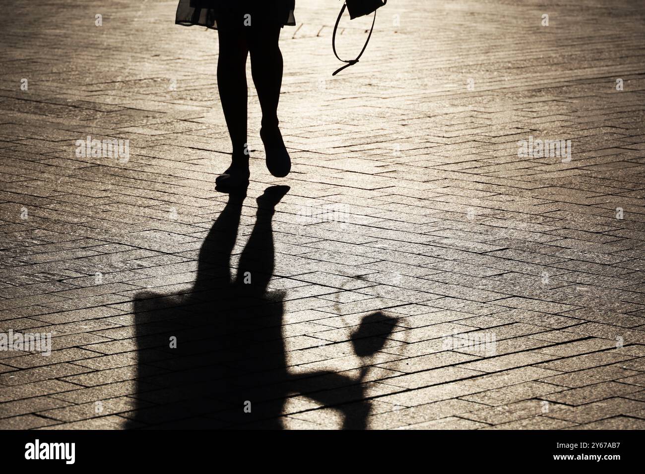 Black silhouette and shadow of lonely slim woman walking on a street ...