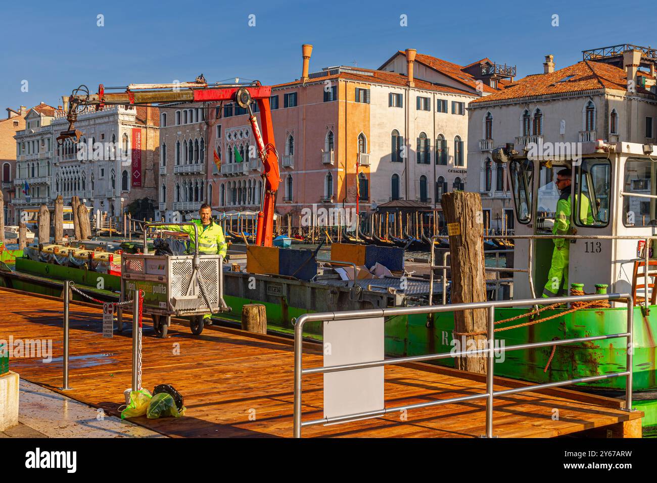 Men on a refuse boat with a hydraulic lifting arm collecting and ...