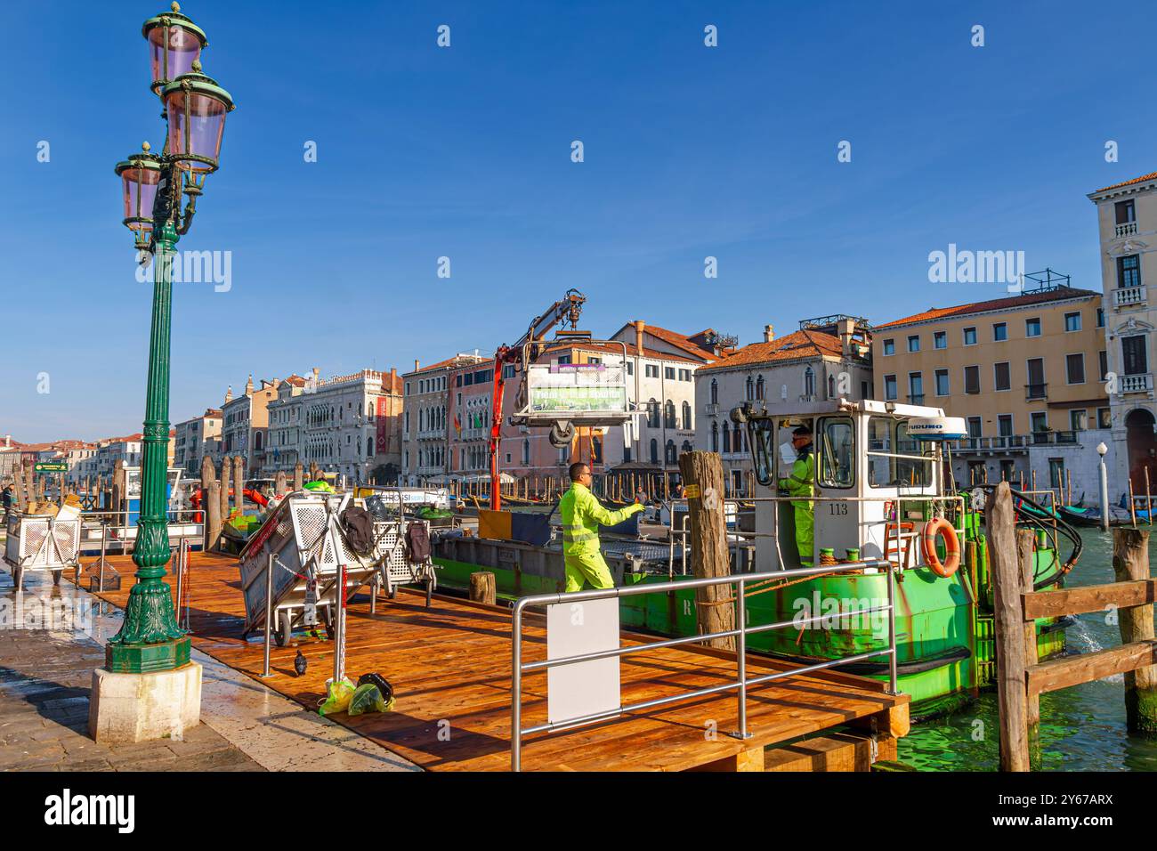 Men on a refuse boat with a hydraulic lifting arm collecting and ...