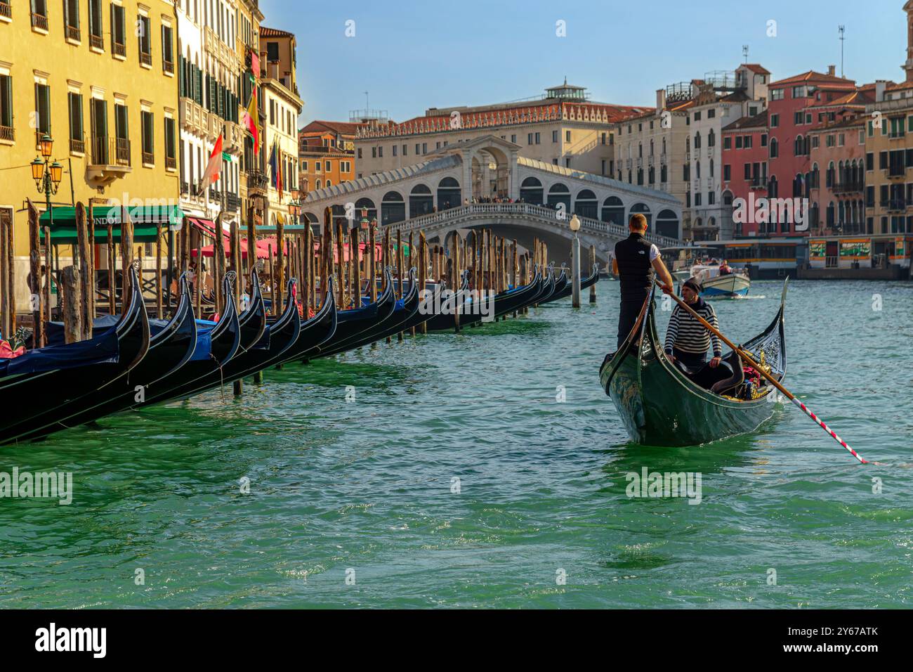 A gondolier steers his gondola past a line of moored gondolas on The ...