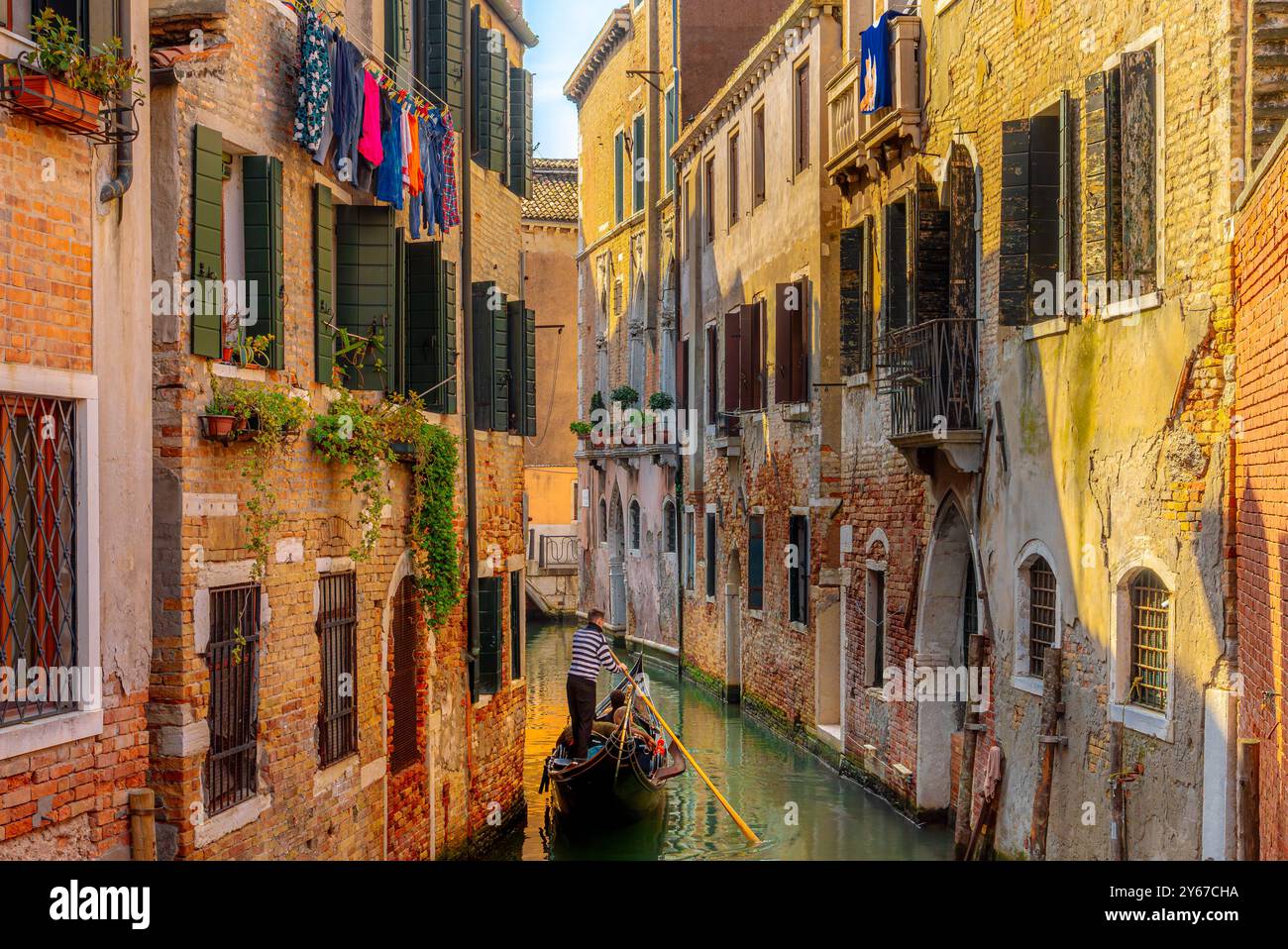 A gondolier steers his gondola along Rio de la Verona,a narrow canal in ...