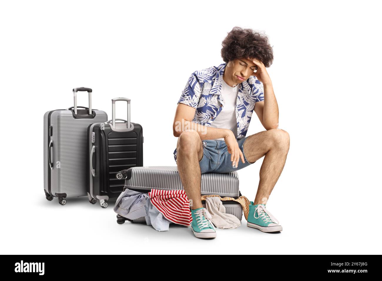 Sad young man sitting on overpacked suitcase isolated on white ...