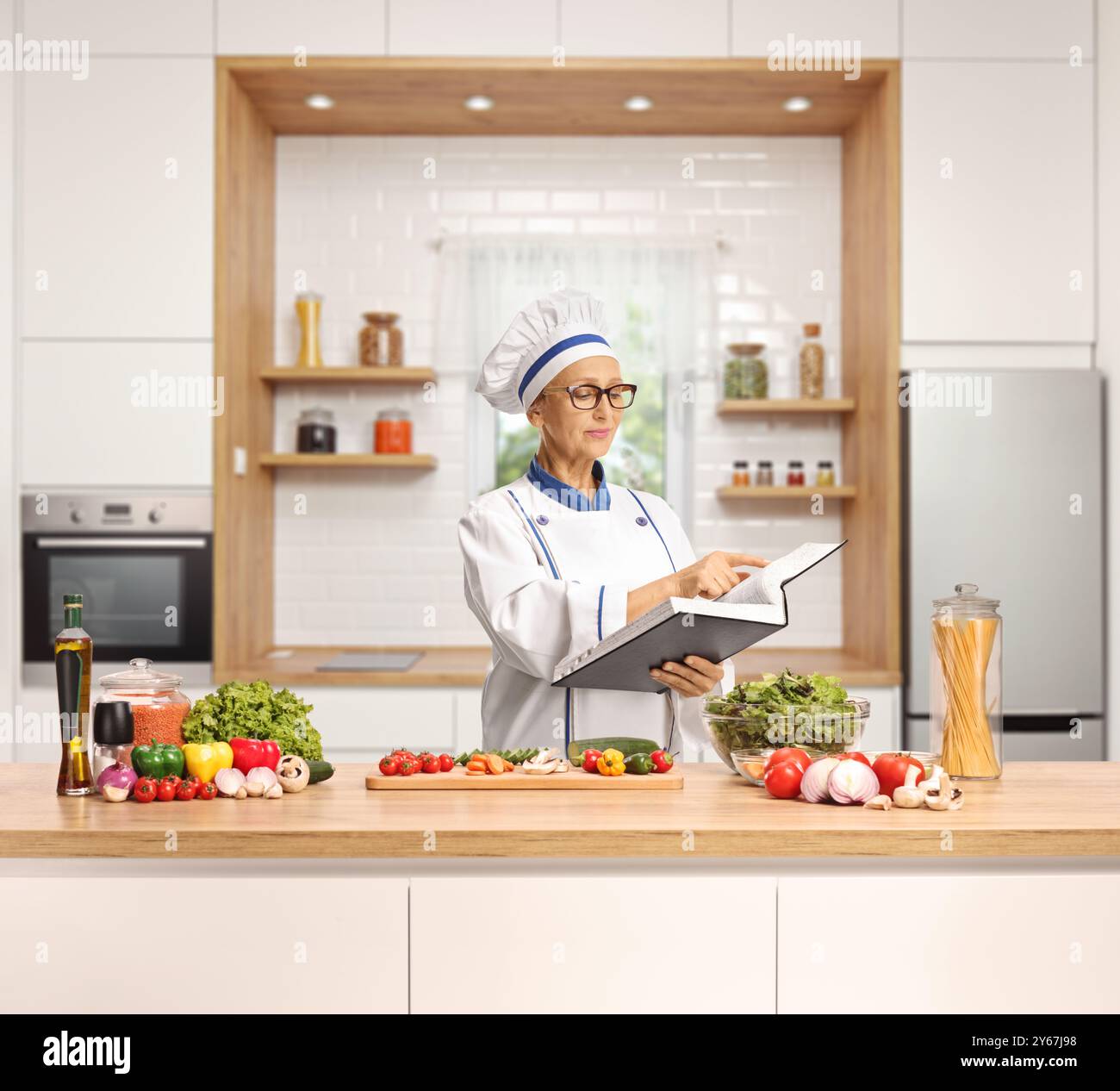 Female professional chef reading a recipe in a cook book and preparing ...