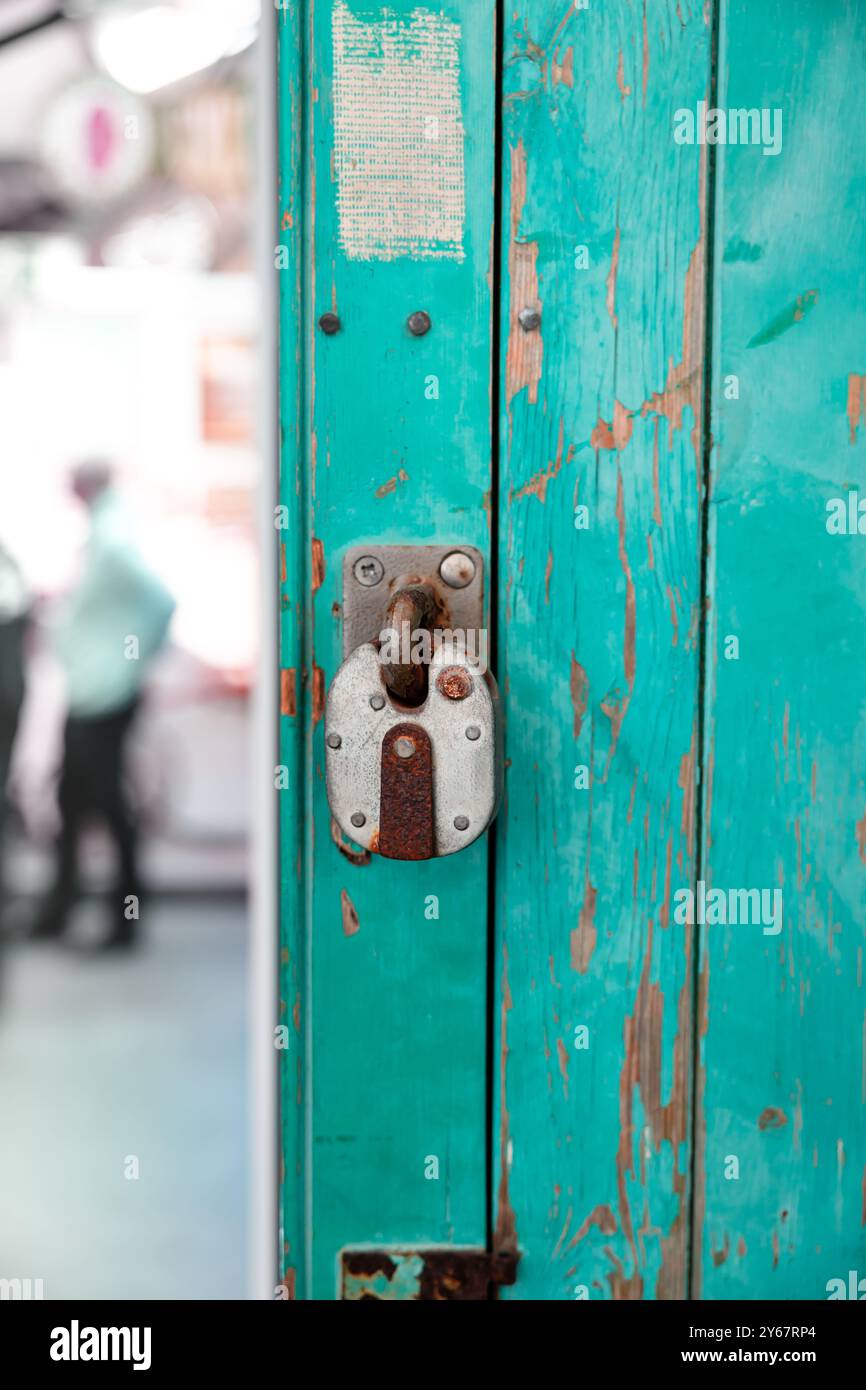 a close-up view of a worn, rusted padlock on a turquiose or teal blue ...